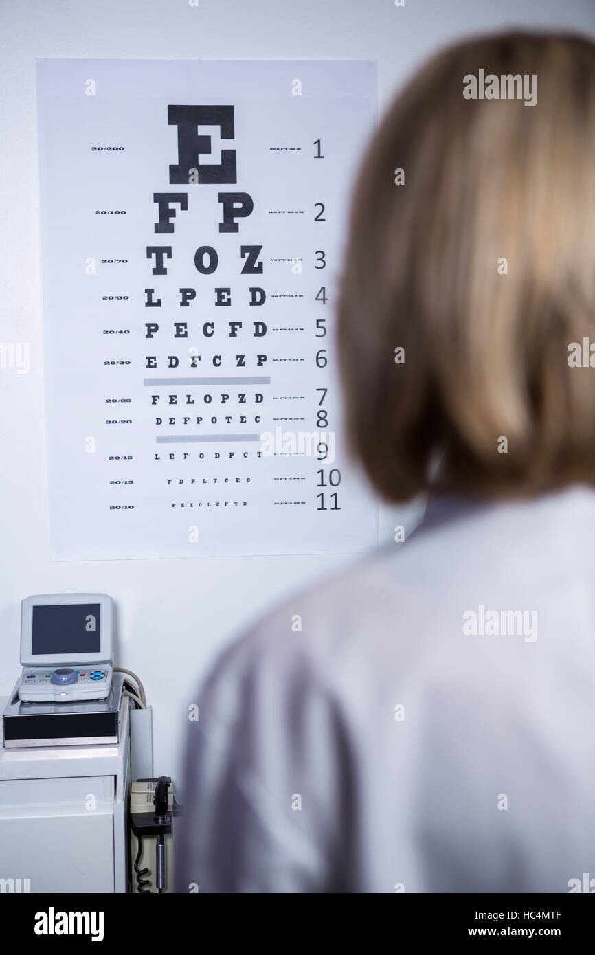 Optometrist looking at eye chart Stock Photo - Alamy