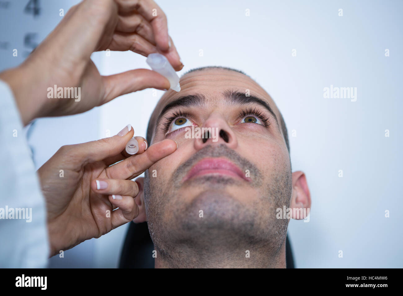 Optometrist putting drops into patients eyes Stock Photo - Alamy