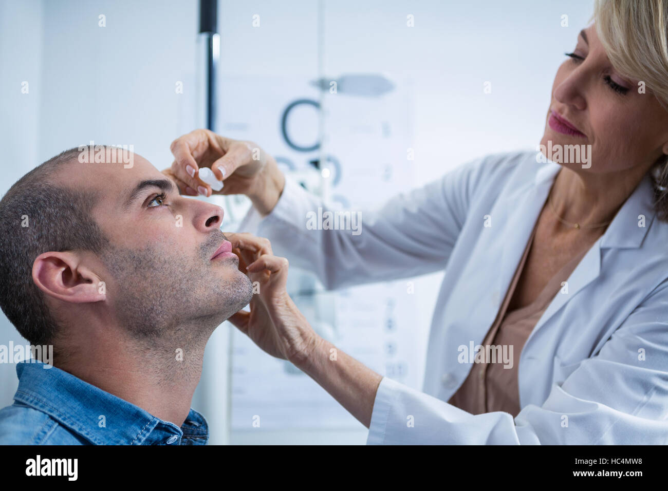 Optometrist putting drops into patients eyes Stock Photo - Alamy