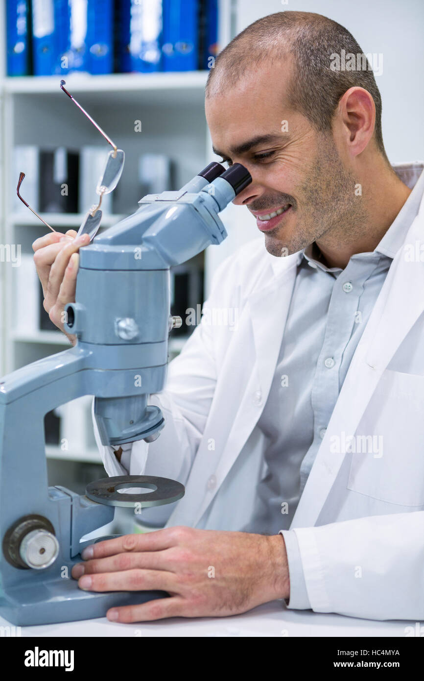Smiling male optometrist looking through microscope Stock Photo - Alamy