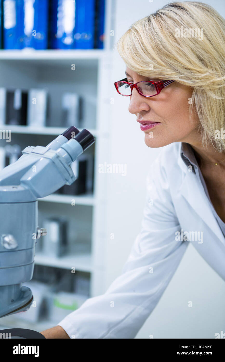 Female optometrist looking through microscope Stock Photo - Alamy