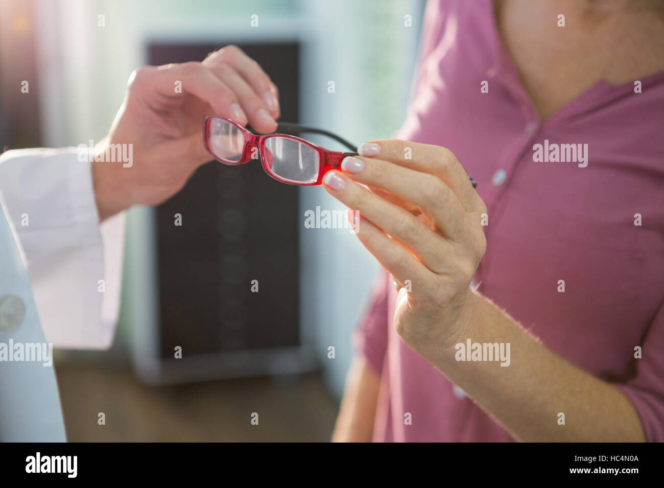 Optometrist giving spectacles to customer in optical store Stock Photo ...