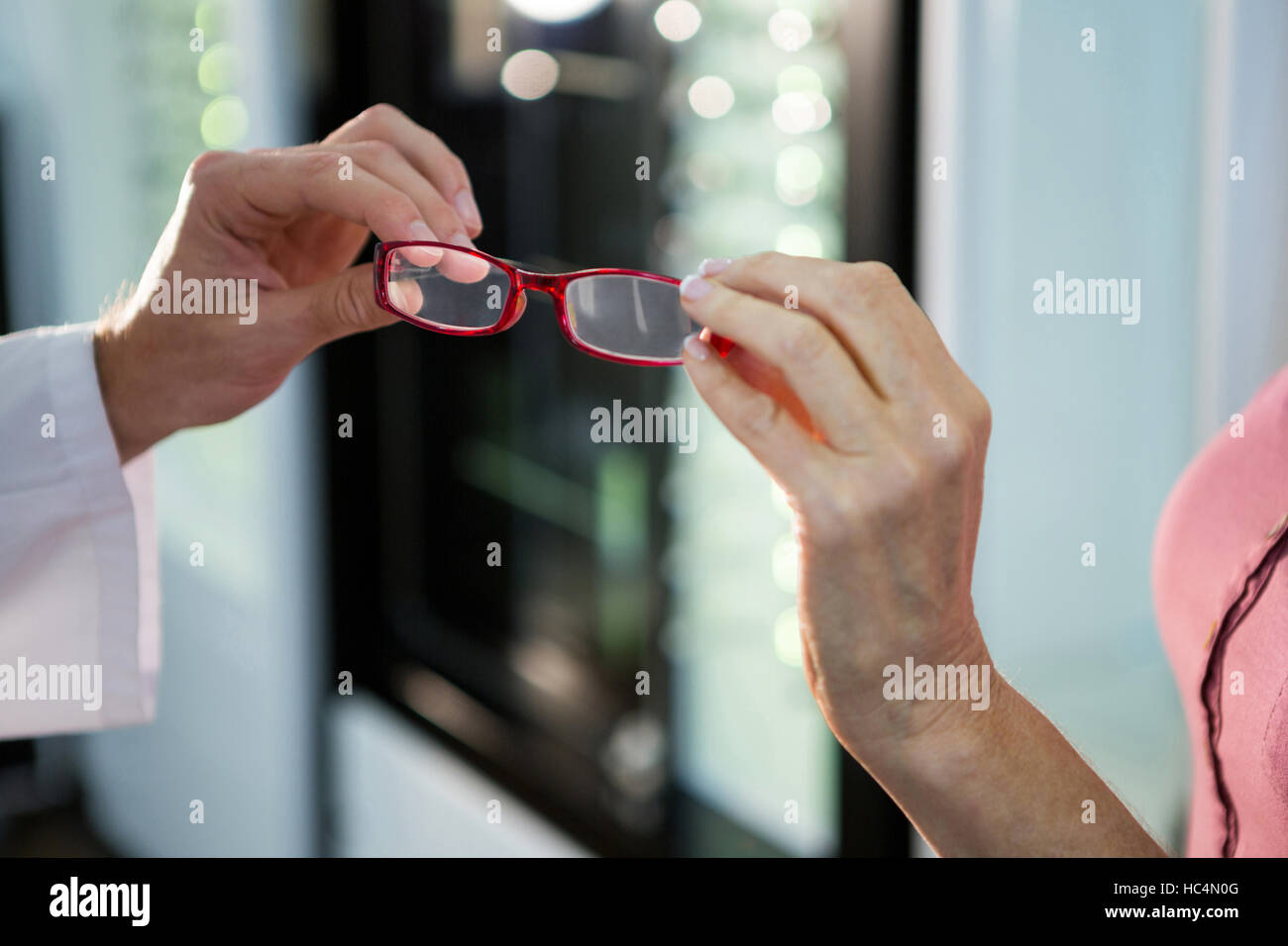 Optometrist giving spectacles to customer in optical store Stock Photo ...
