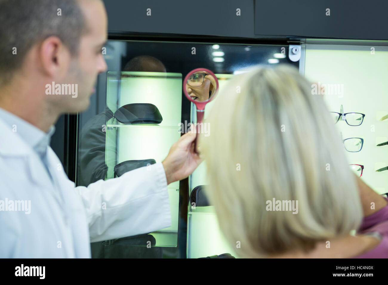 Female customer wearing spectacles and checking in mirror Stock Photo ...