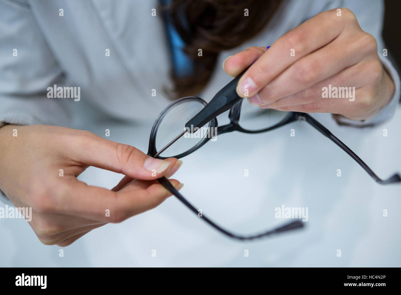 Optician repairing spectacles with tool Stock Photo - Alamy