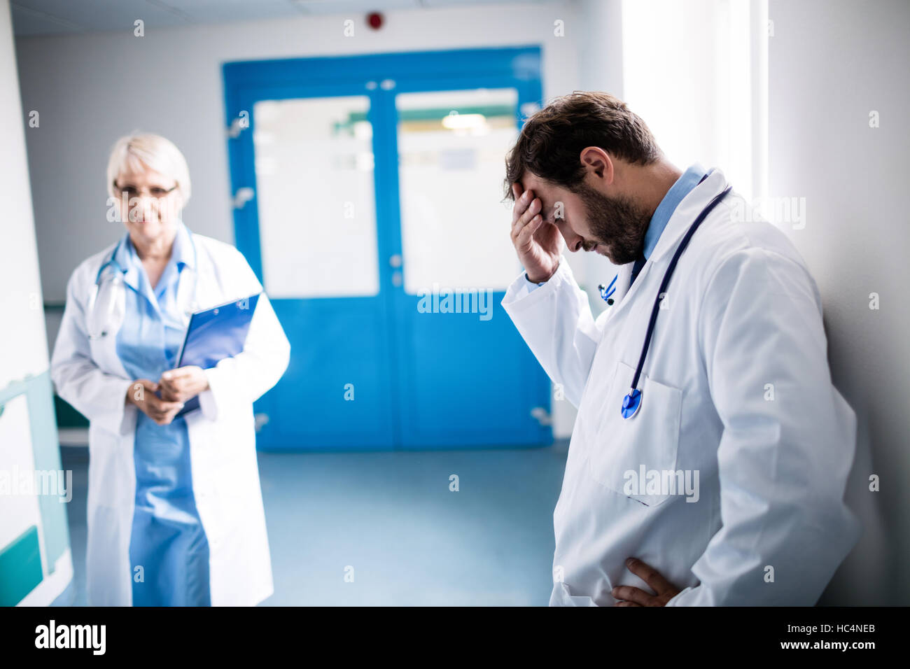 Sad doctor leaning against the wall Stock Photo - Alamy