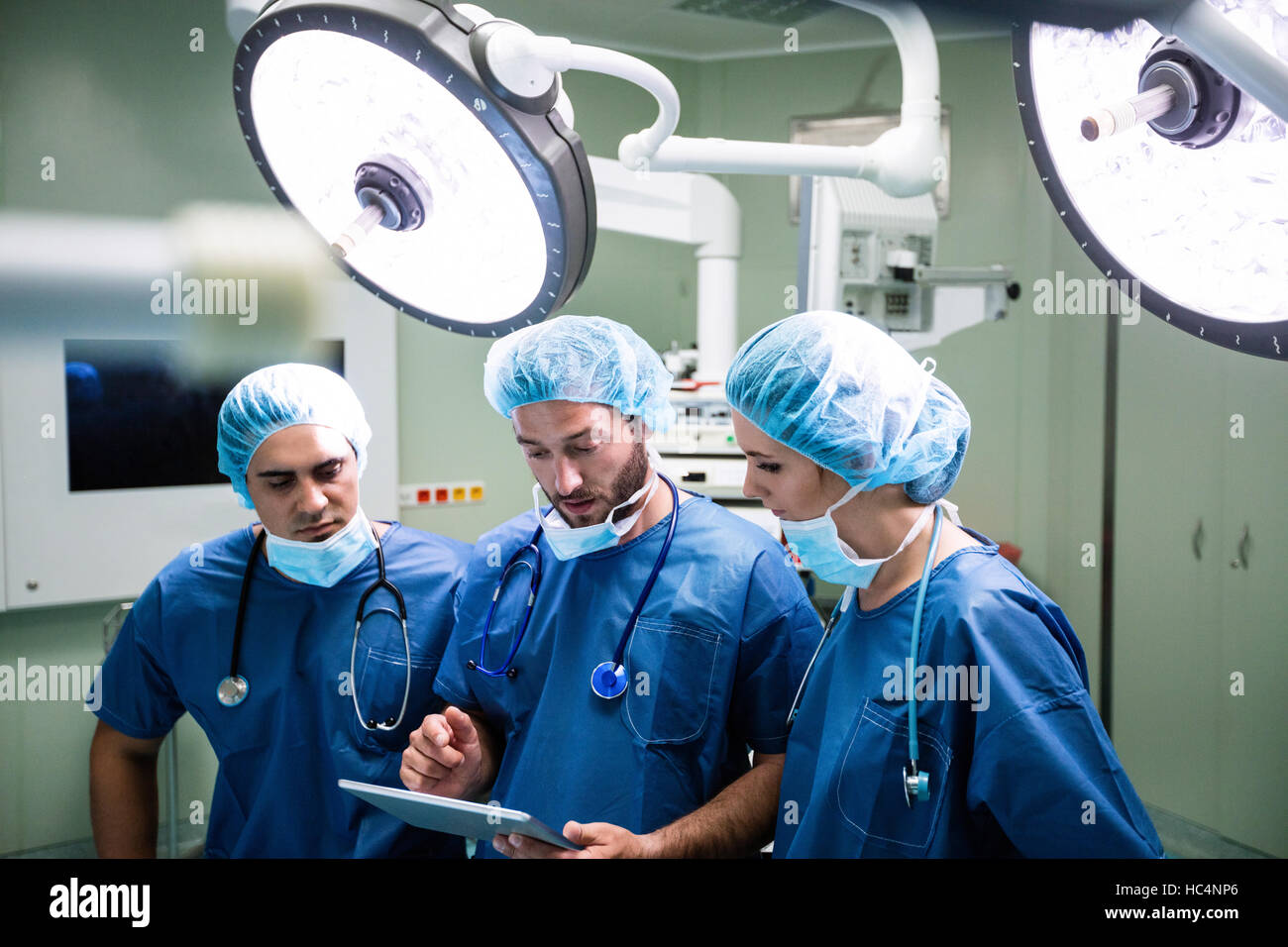 Surgeons discussing over digital tablet in operation room Stock Photo ...