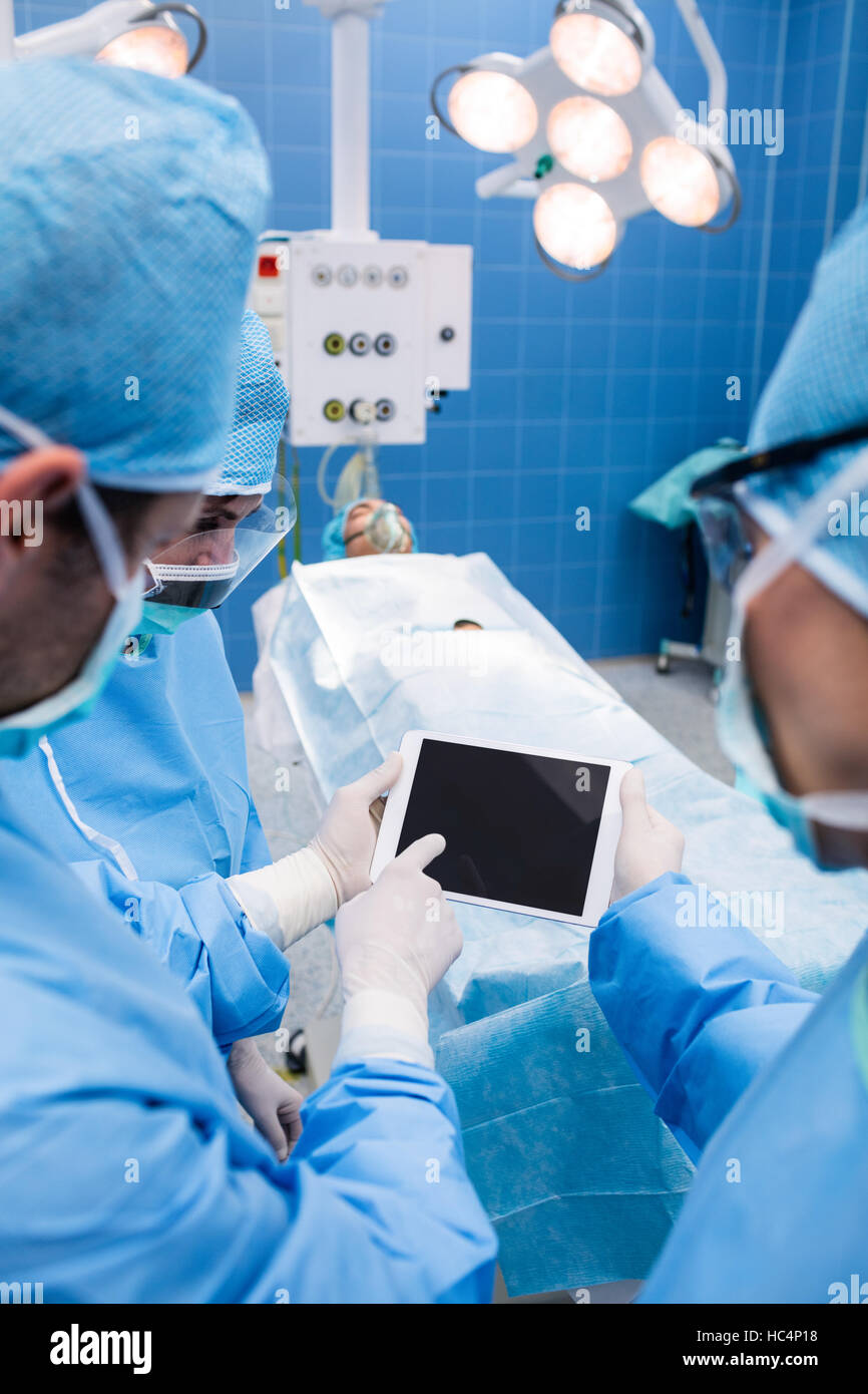 Surgeons using digital tablet and patient lying on operation bed Stock ...