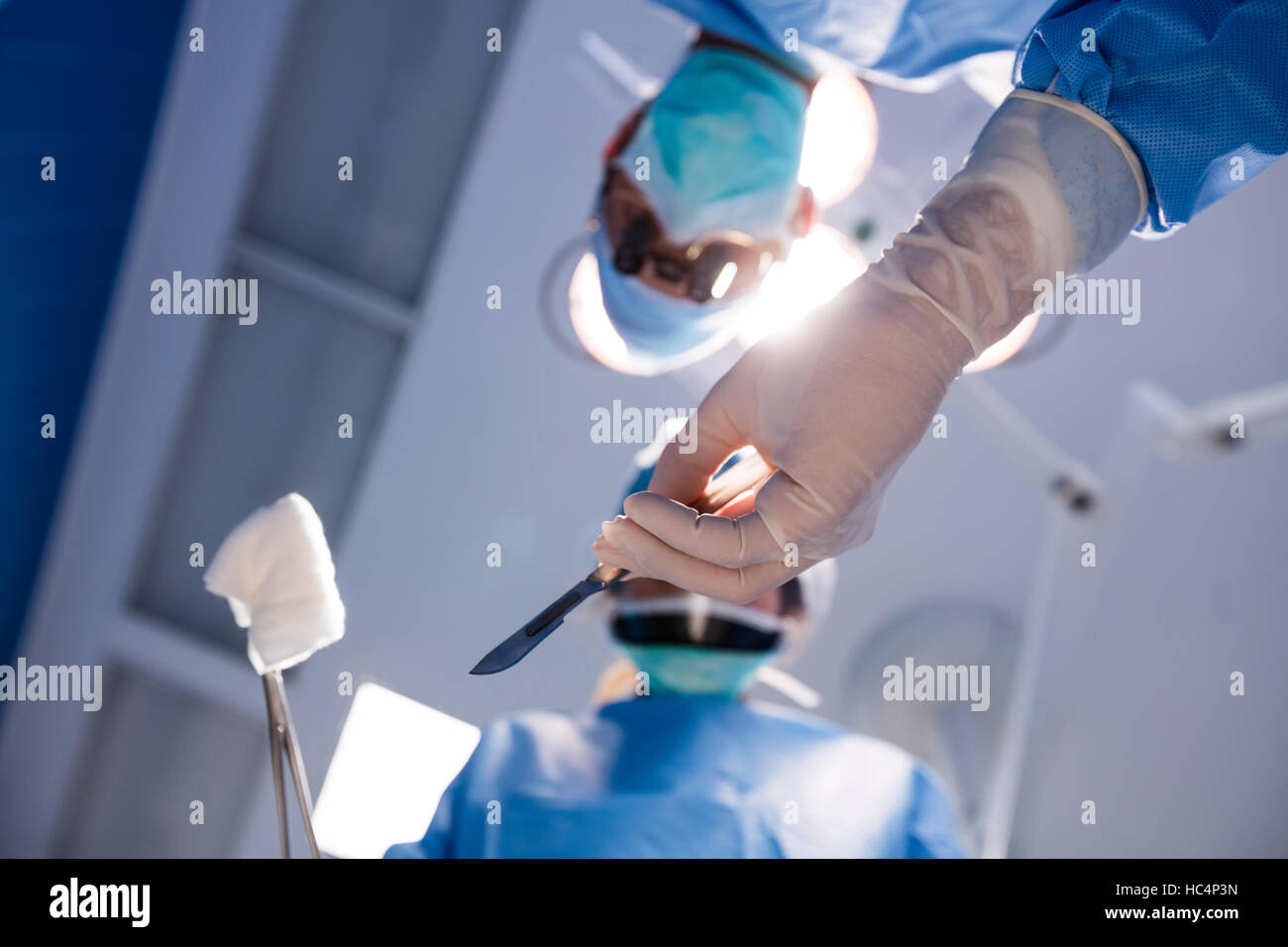 Surgeons holding surgical clamp with cotton swab in operation room ...