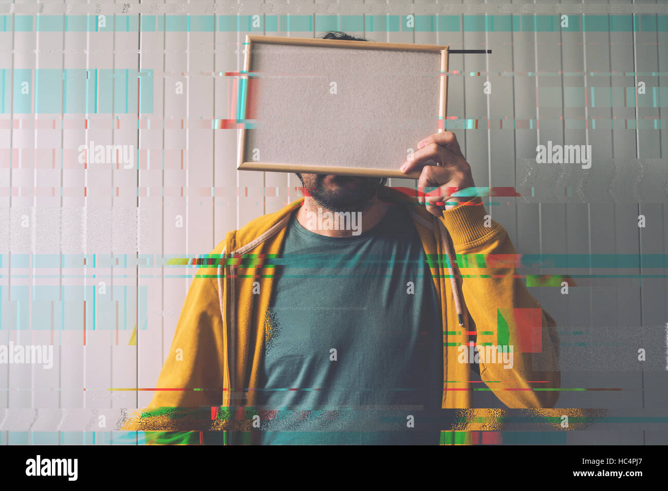 Unrecognizable man posing with blank picture frame over his face as ...