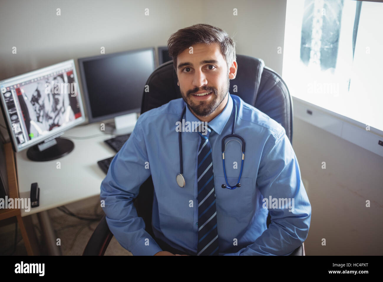 Portrait of doctor sitting at his desk Stock Photo - Alamy