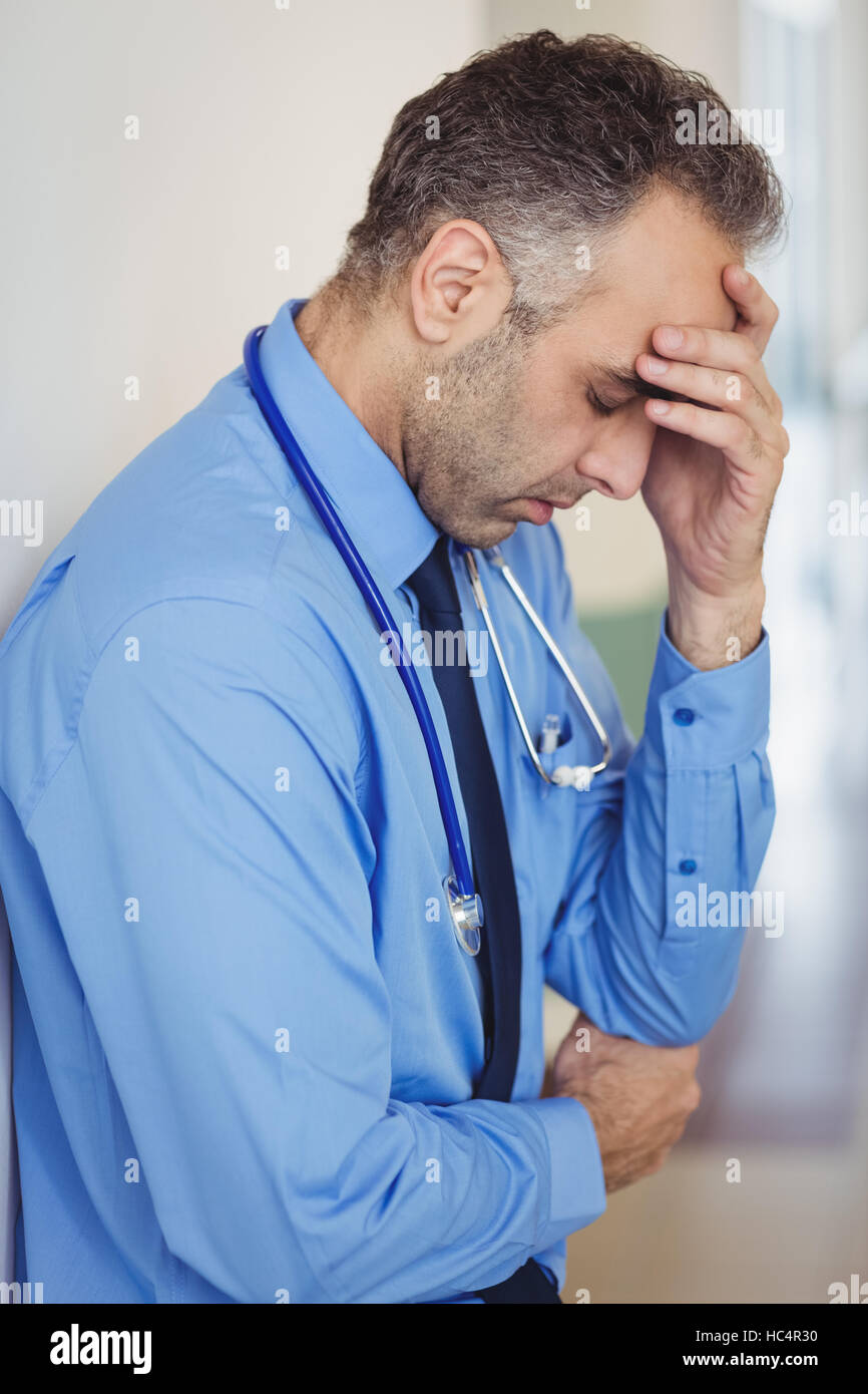 Sad doctor leaning against the wall Stock Photo - Alamy