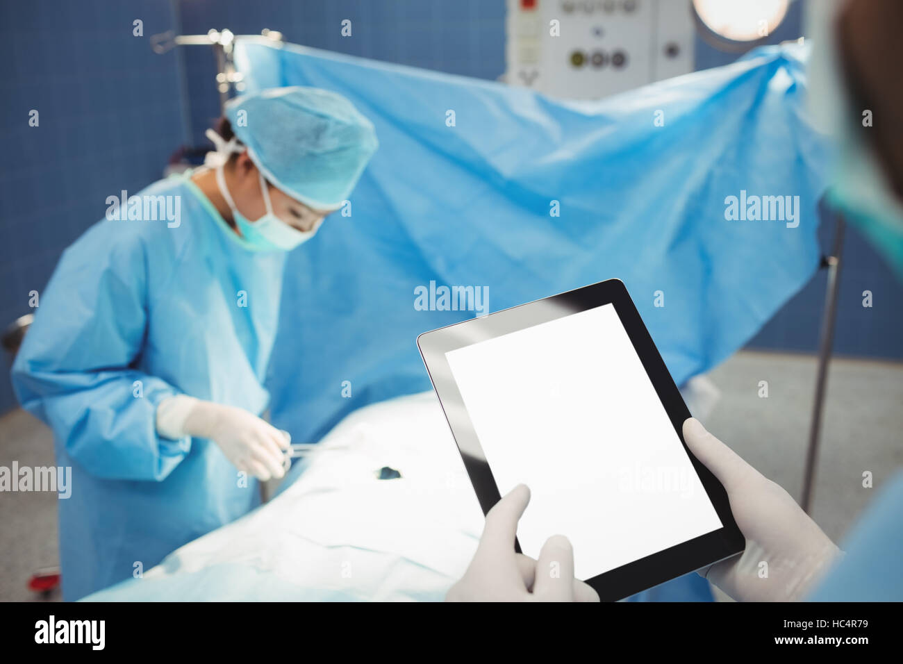 Surgeon using digital while nurse operating patient in operation room ...