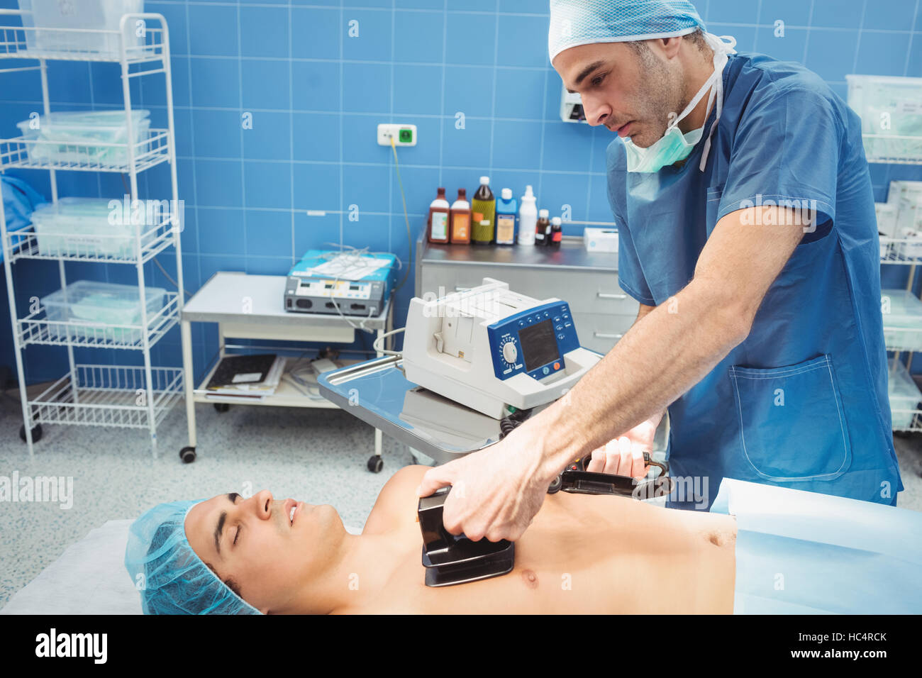Male surgeon resuscitating an unconscious patient with a defibrillator ...