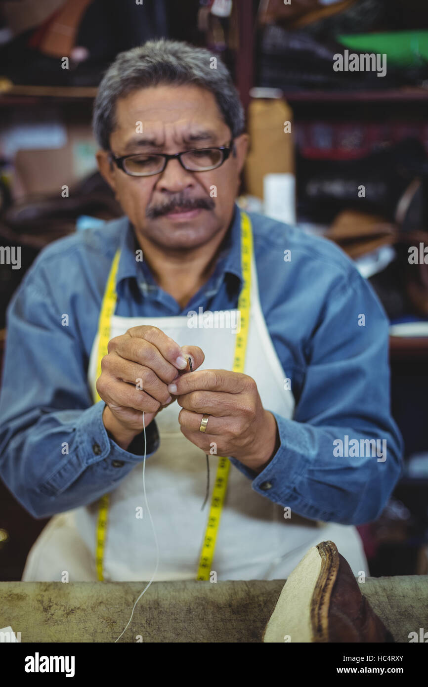 Shoemaker putting thread in the needle Stock Photo - Alamy