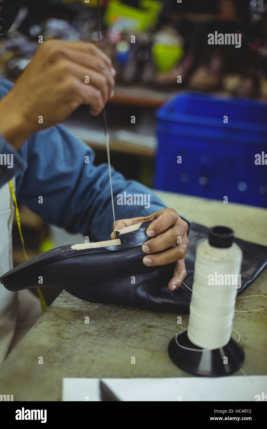 Shoemaker stitching shoe sole with needle Stock Photo - Alamy