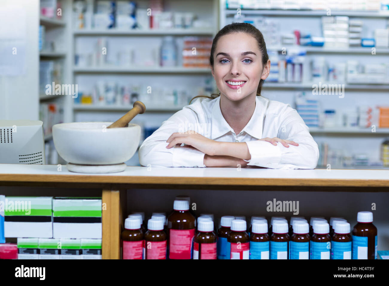 Smiling pharmacist sitting at counter in pharmacy Stock Photo - Alamy