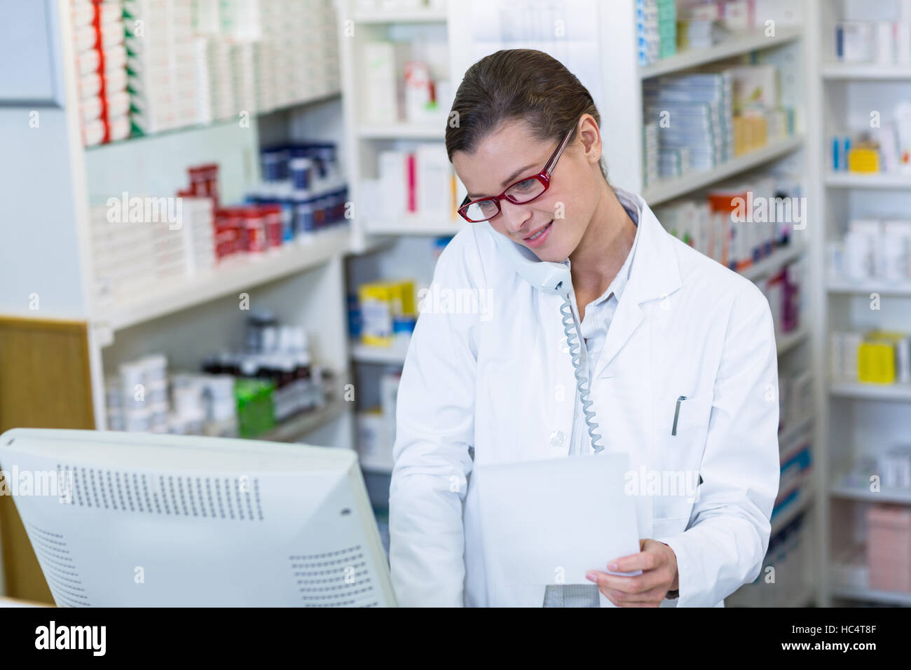 Pharmacist holding prescription paper while talking on phone Stock ...
