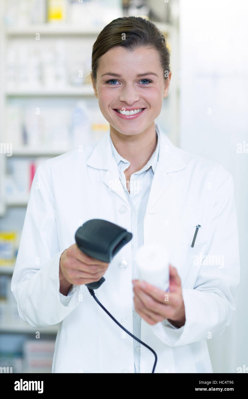 Smiling pharmacist using barcode scanner on medicine bottle in pharmacy ...