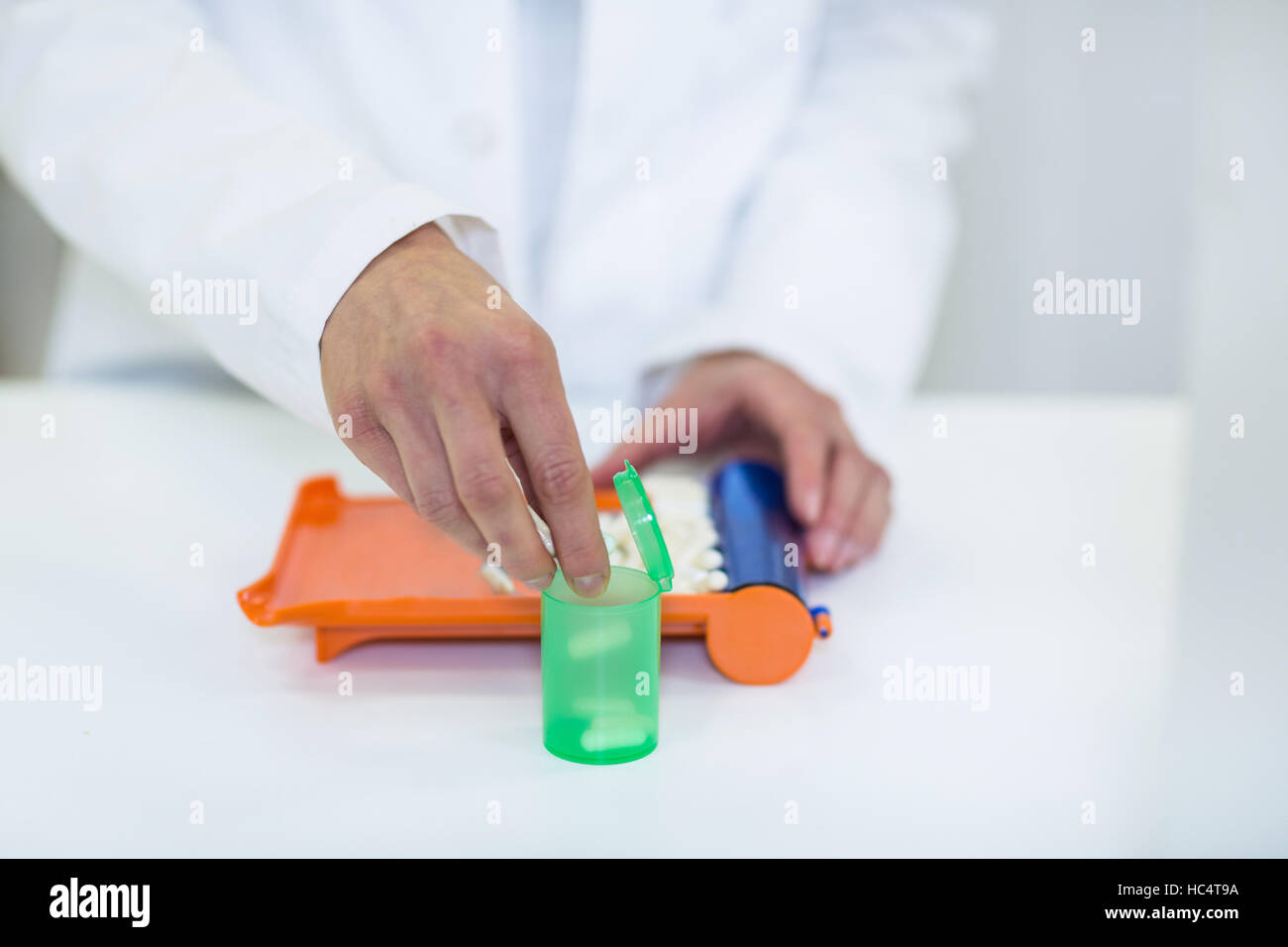 Pharmacist putting pill in container at pharmacy Stock Photo - Alamy