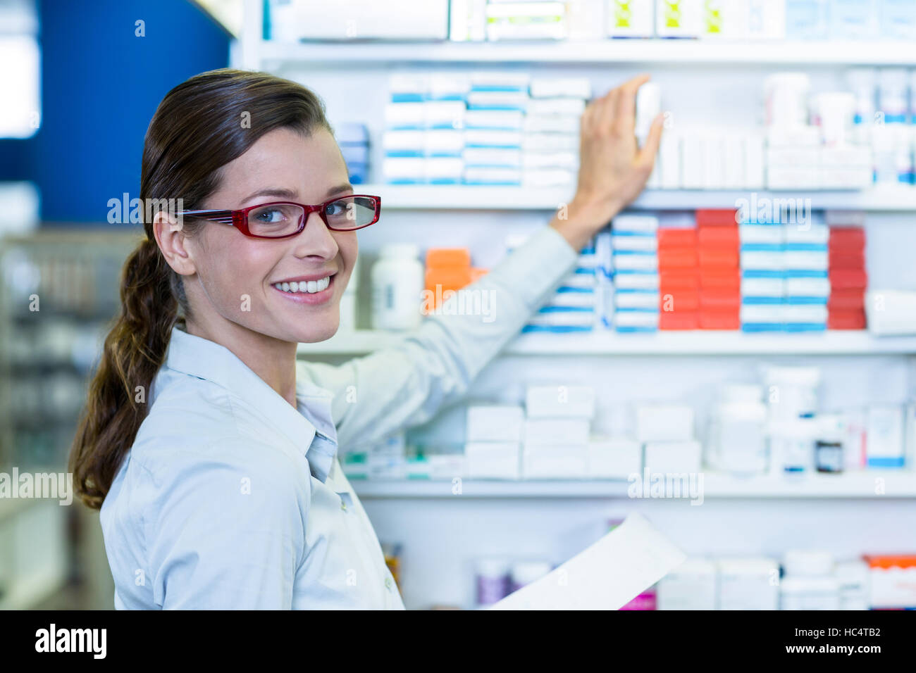 Pharmacist holding prescription while checking medicine in pharmacy ... Pharmacist holding prescription while checking medicine in pharmacy ...