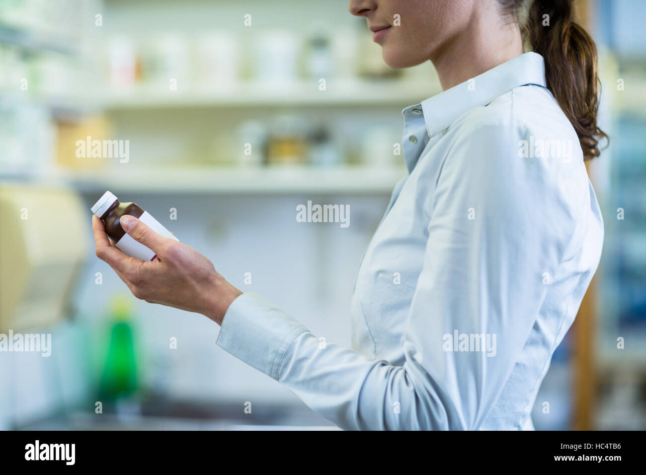 Pharmacist checking a bottle of drug in pharmacy Stock Photo - Alamy