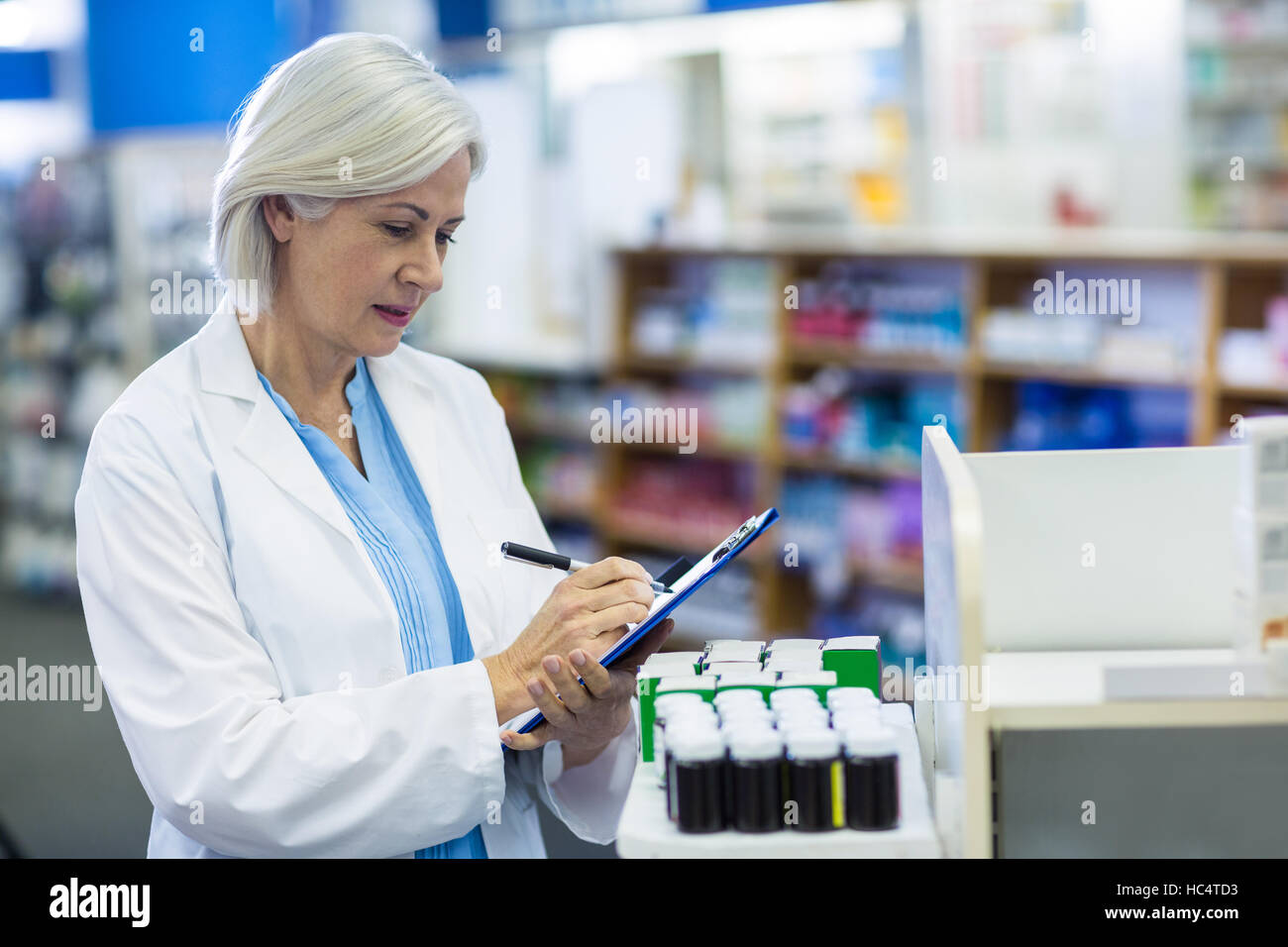 Pharmacist writing on clipboard Stock Photo - Alamy