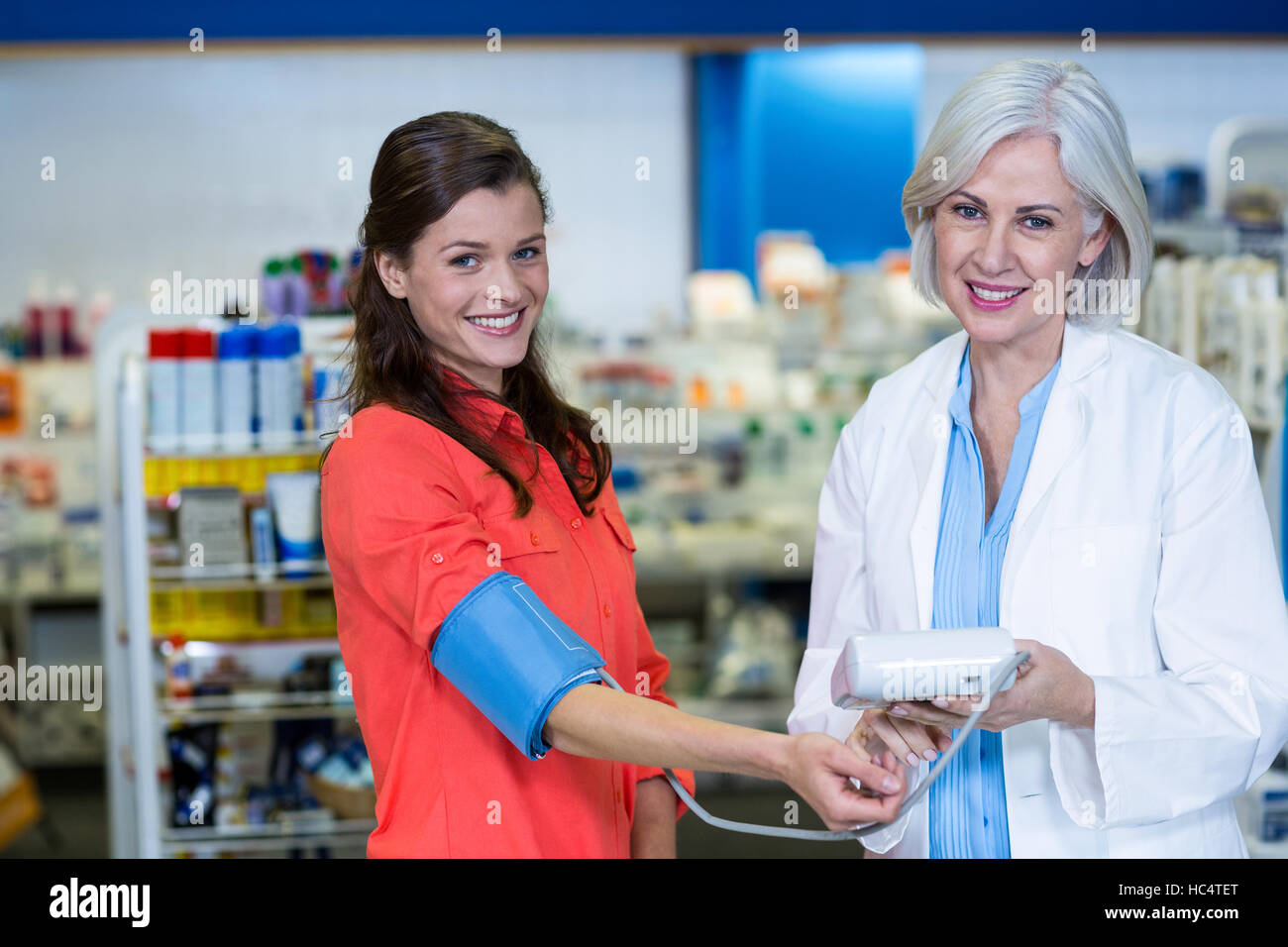 Pharmacist checking blood pressure of customer in pharmacy Stock Photo ...