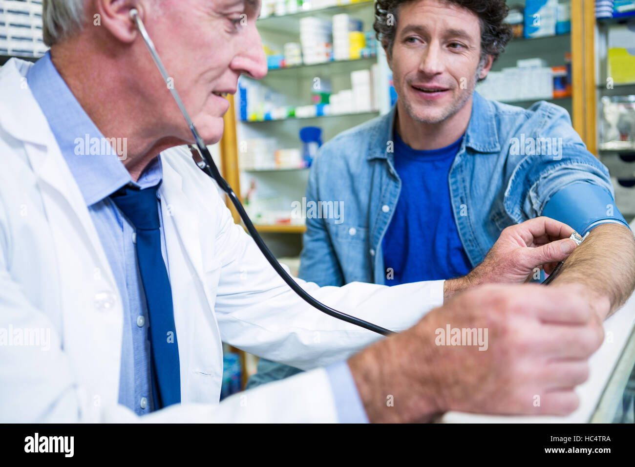 Pharmacist checking blood pressure of customer Stock Photo - Alamy