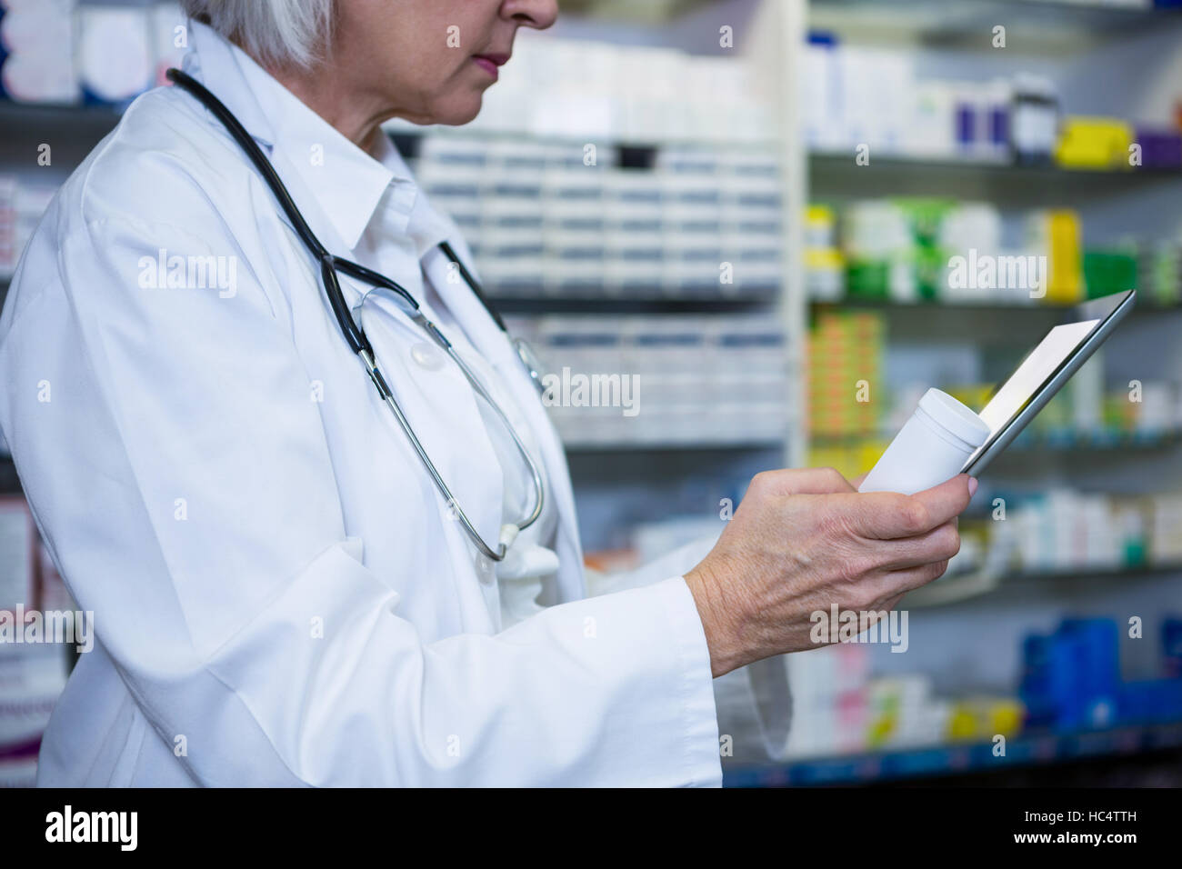 Pharmacist holding digital tablet while checking medicine Stock Photo ...