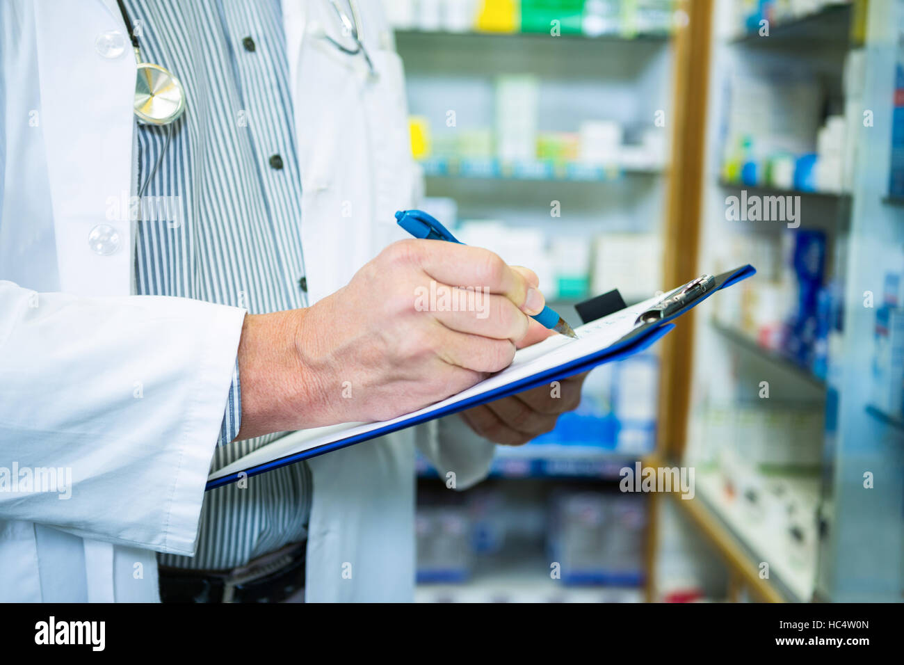 Pharmacist writing on clipboard in pharmacy Stock Photo - Alamy