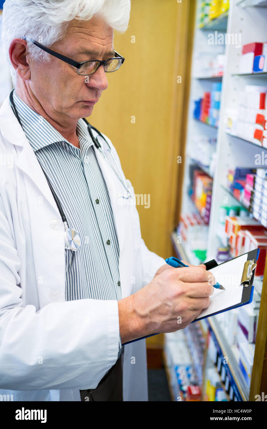 Pharmacist writing on clipboard in pharmacy Stock Photo - Alamy