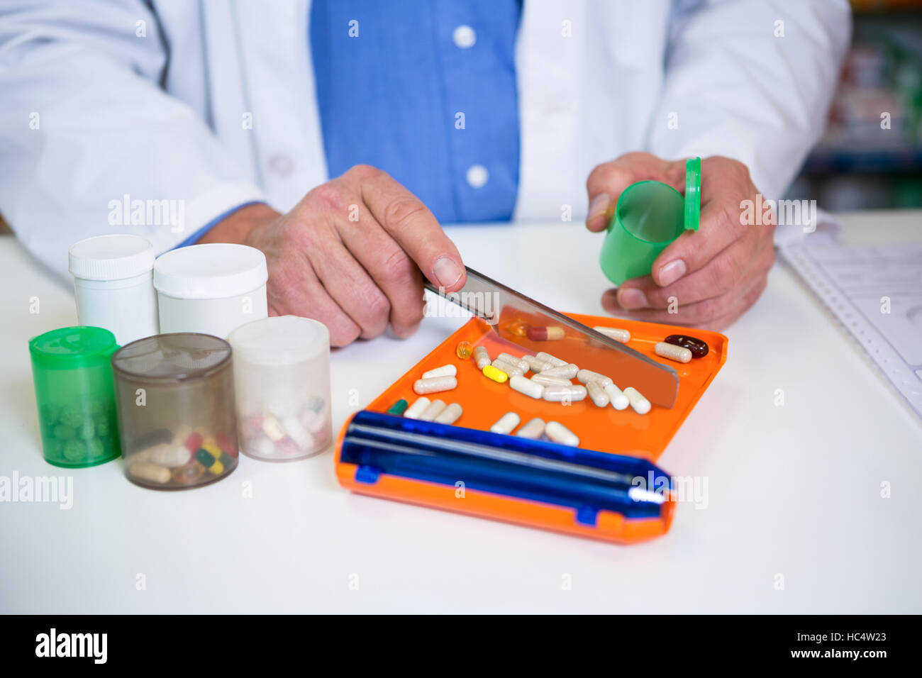 Pharmacist putting pills in container Stock Photo - Alamy