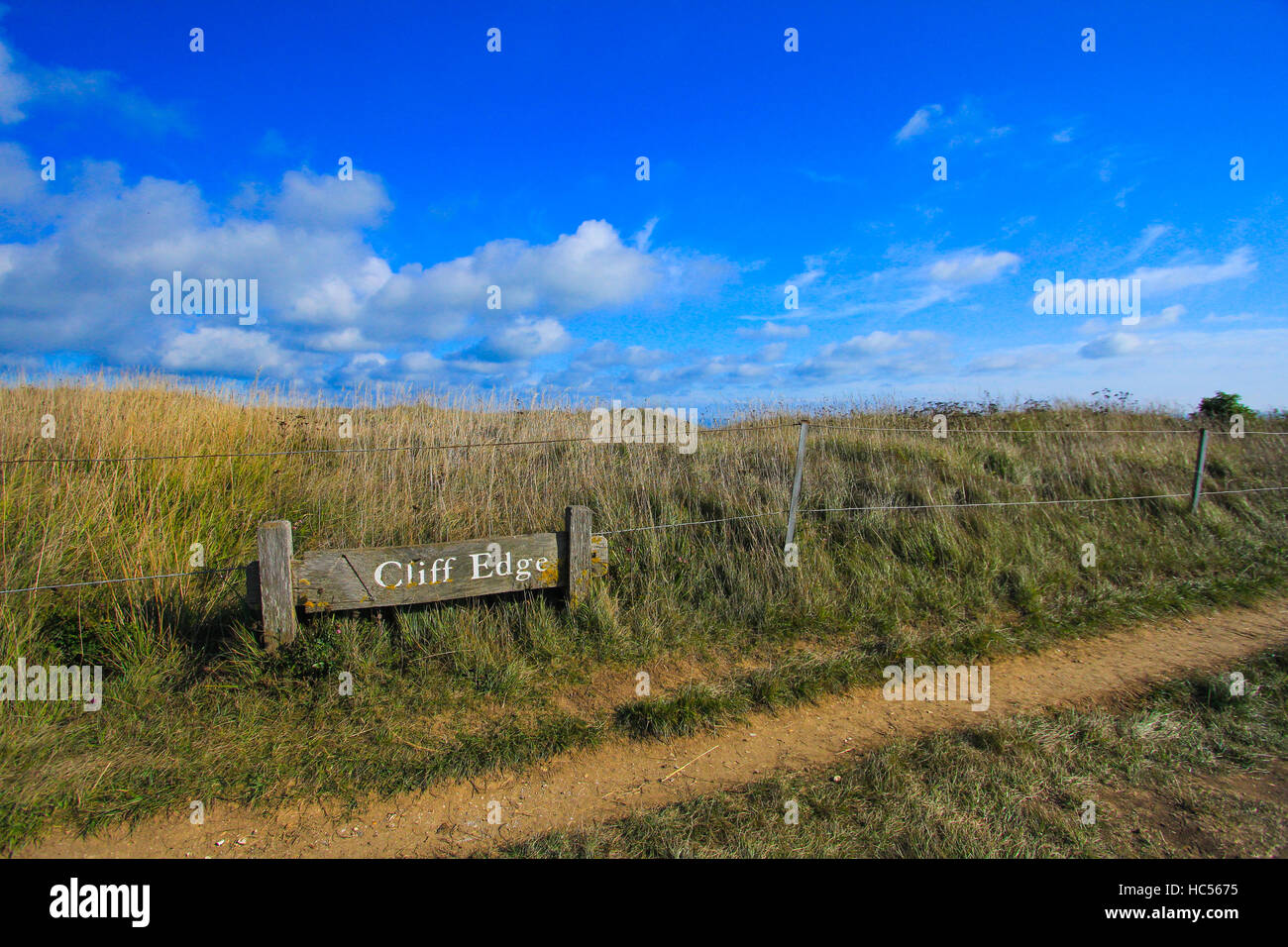 Cliff edge wooden sign with long grassland background Stock Photo - Alamy