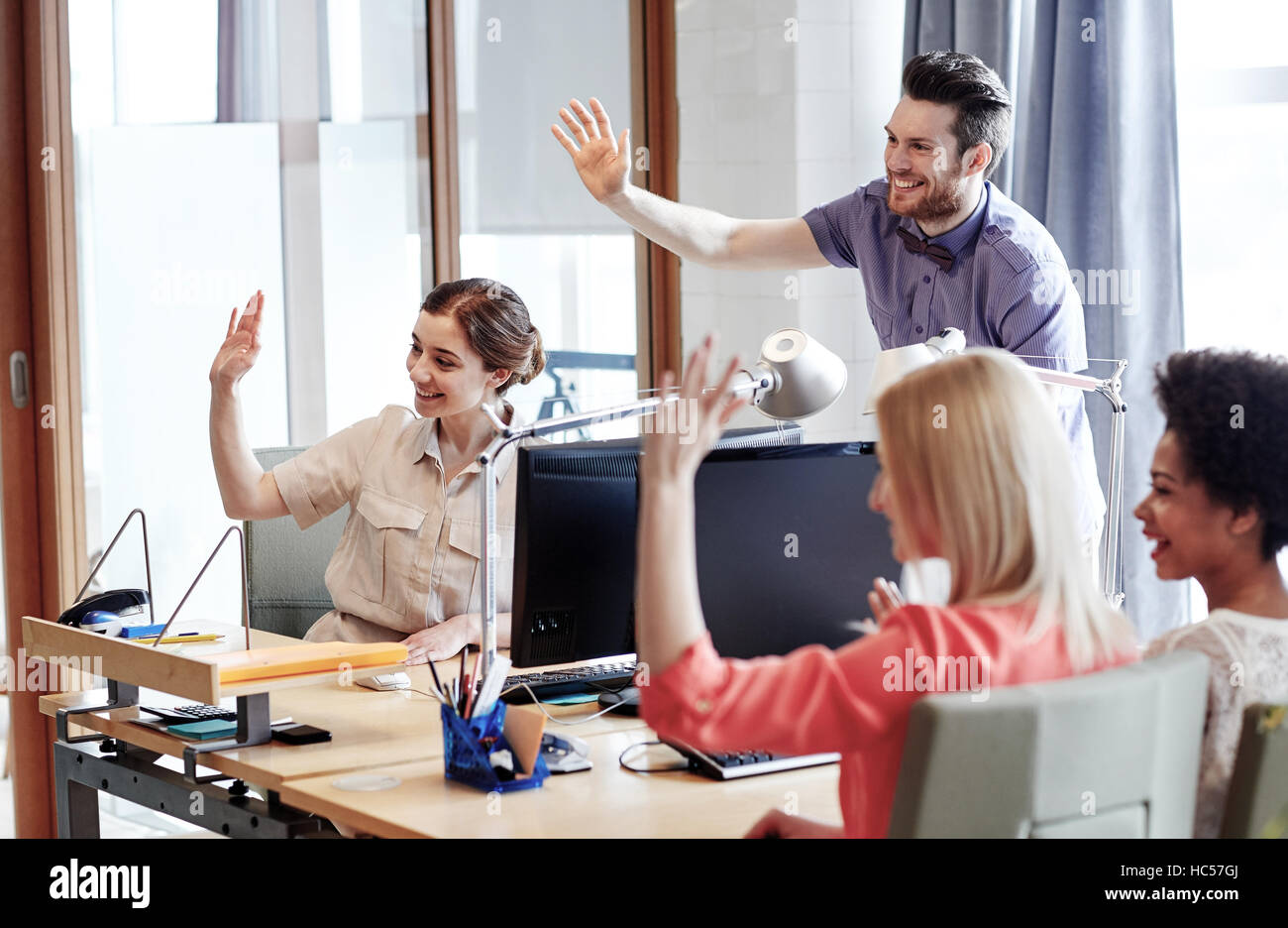 happy creative team waving hands in office Stock Photo - Alamy