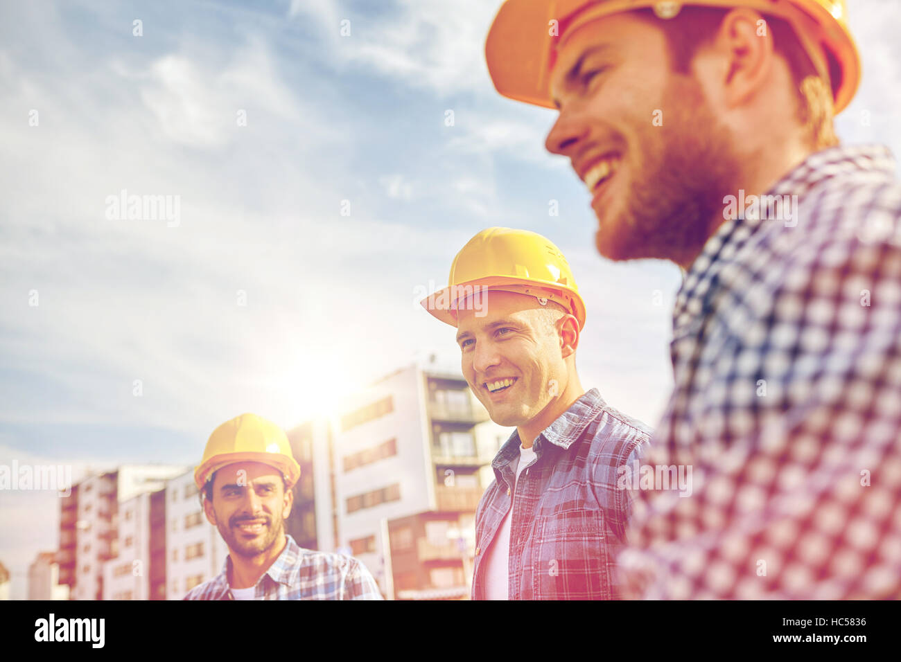 group of smiling builders in hardhats outdoors Stock Photo - Alamy
