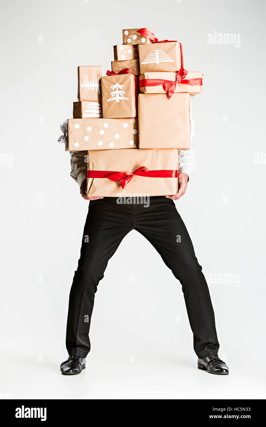 The lot of gift boxes in the hands of young man on white studio ...