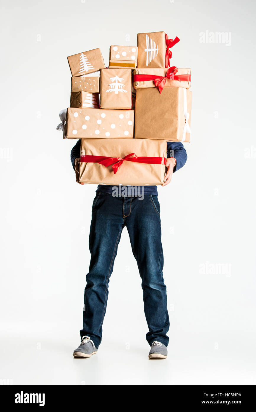 The lot of gift boxes in the hands of young man on white studio ...