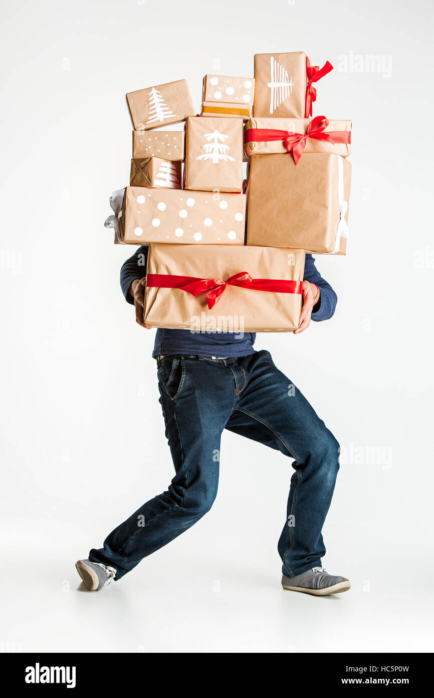 The lot of gift boxes in the hands of young man on white studio ...