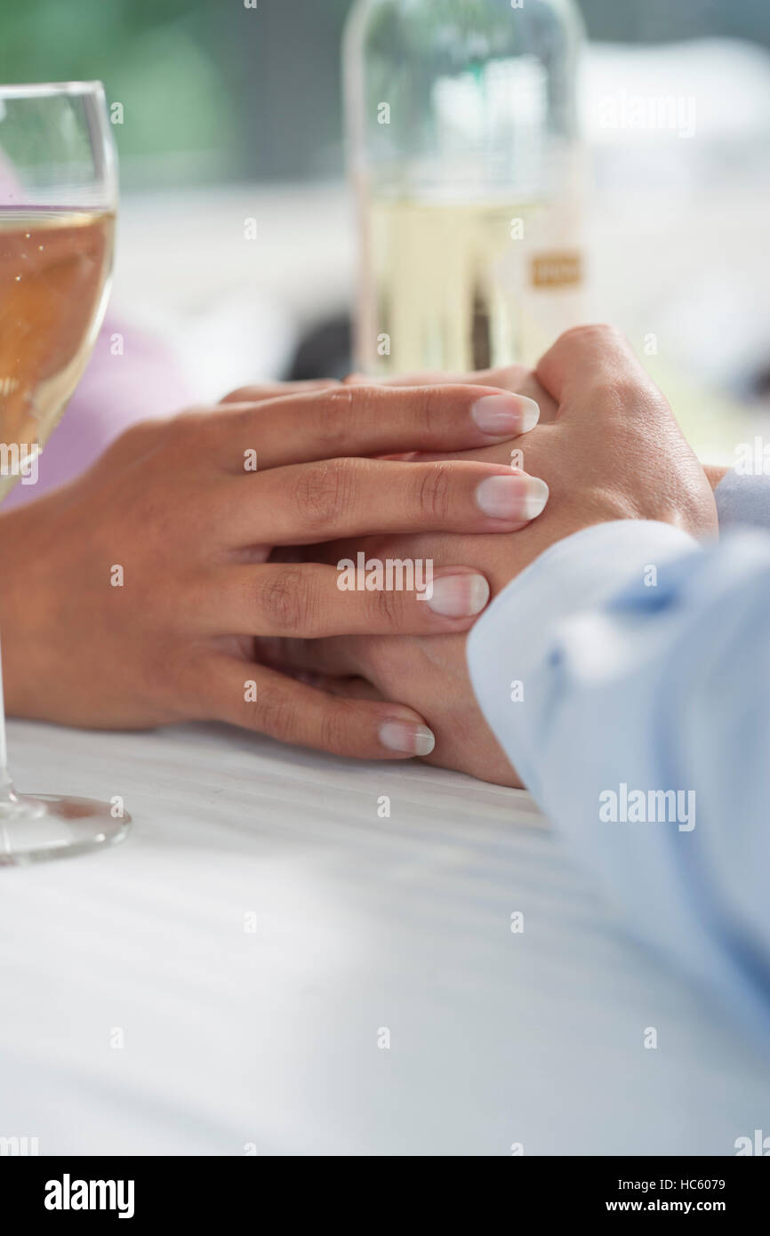 Couple holding hands and drinking white wine in cafe outdoors in the ...