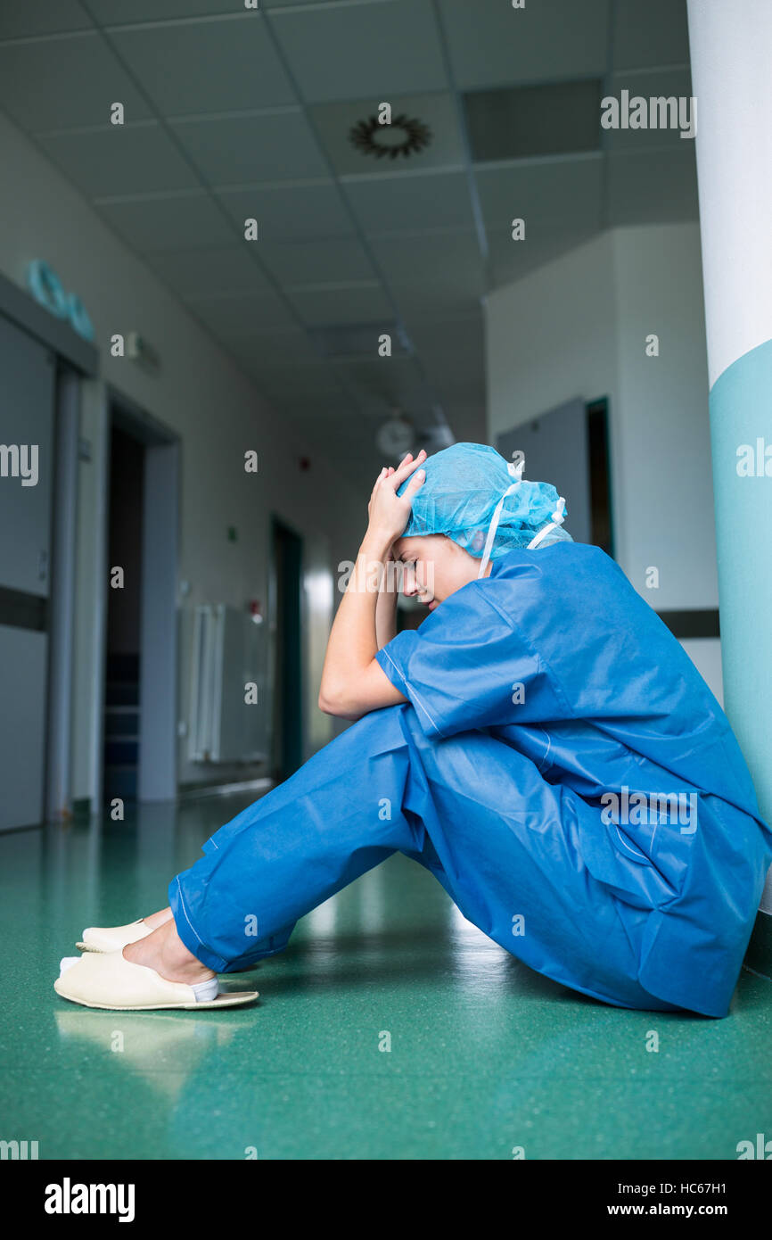 Sad surgeon sitting on floor in corridor Stock Photo - Alamy
