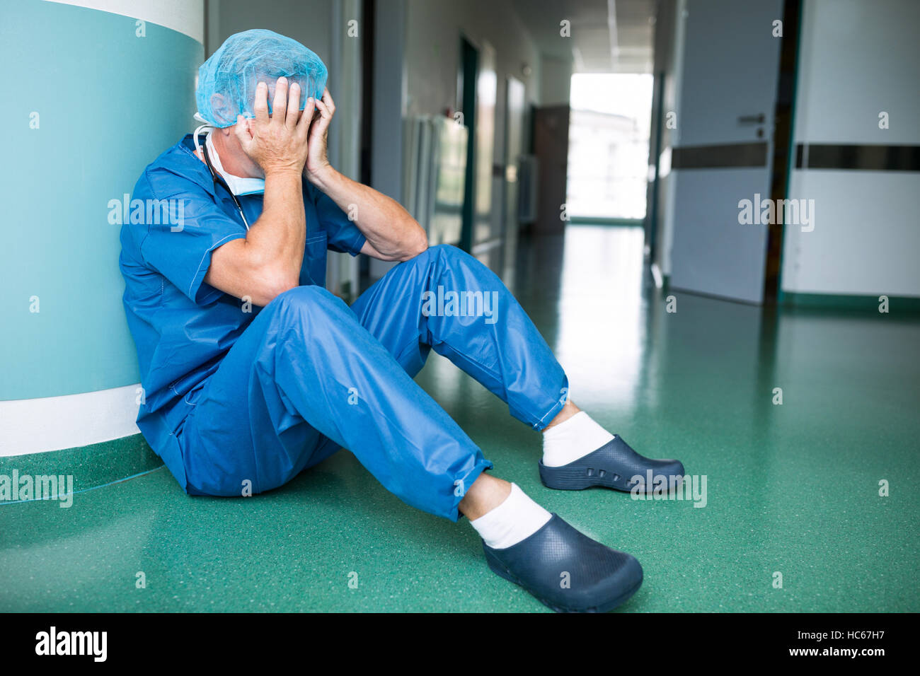 Sad surgeon sitting on floor in corridor Stock Photo - Alamy