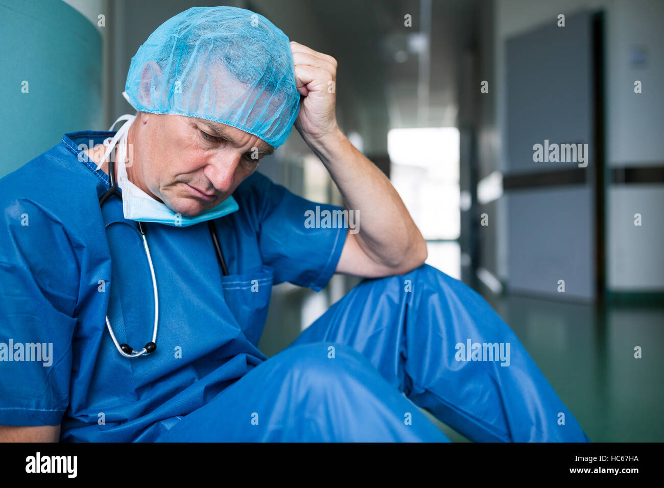 Sad surgeon sitting on floor in corridor Stock Photo - Alamy