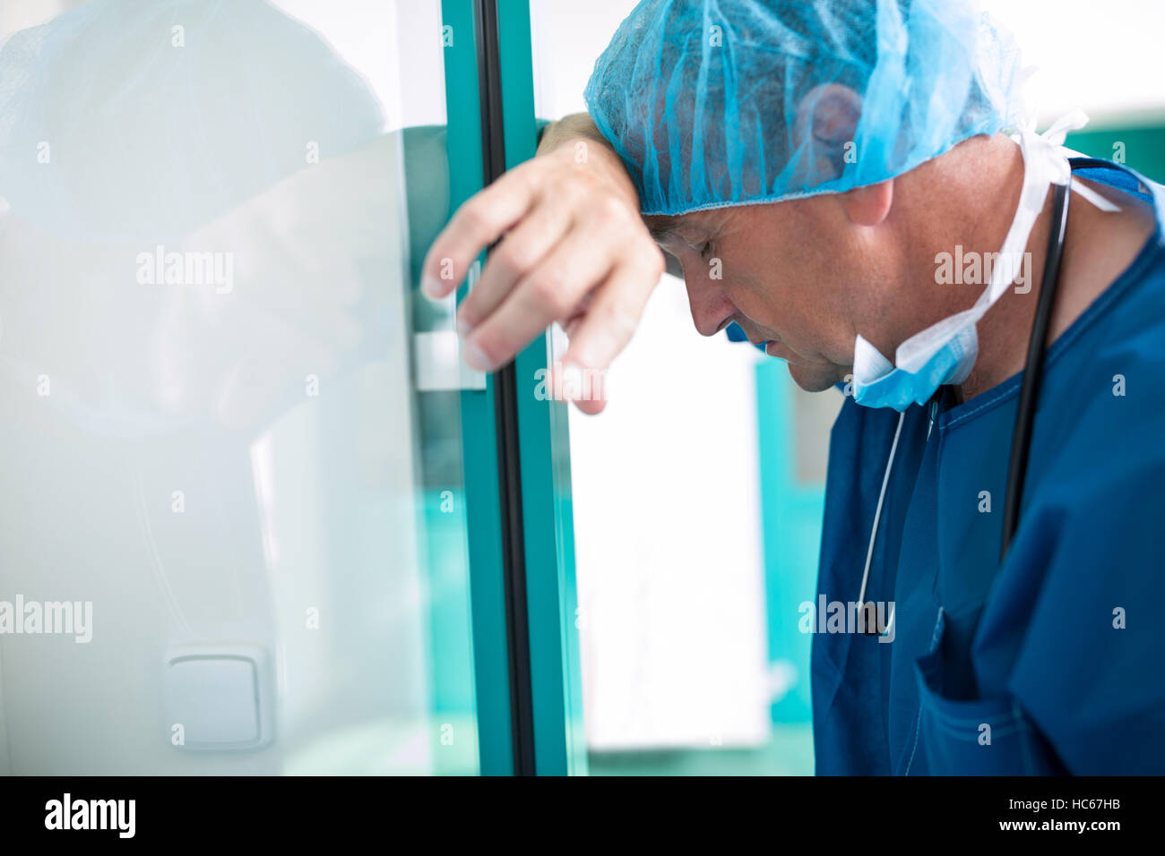 Sad surgeon leaning against the glass door Stock Photo - Alamy