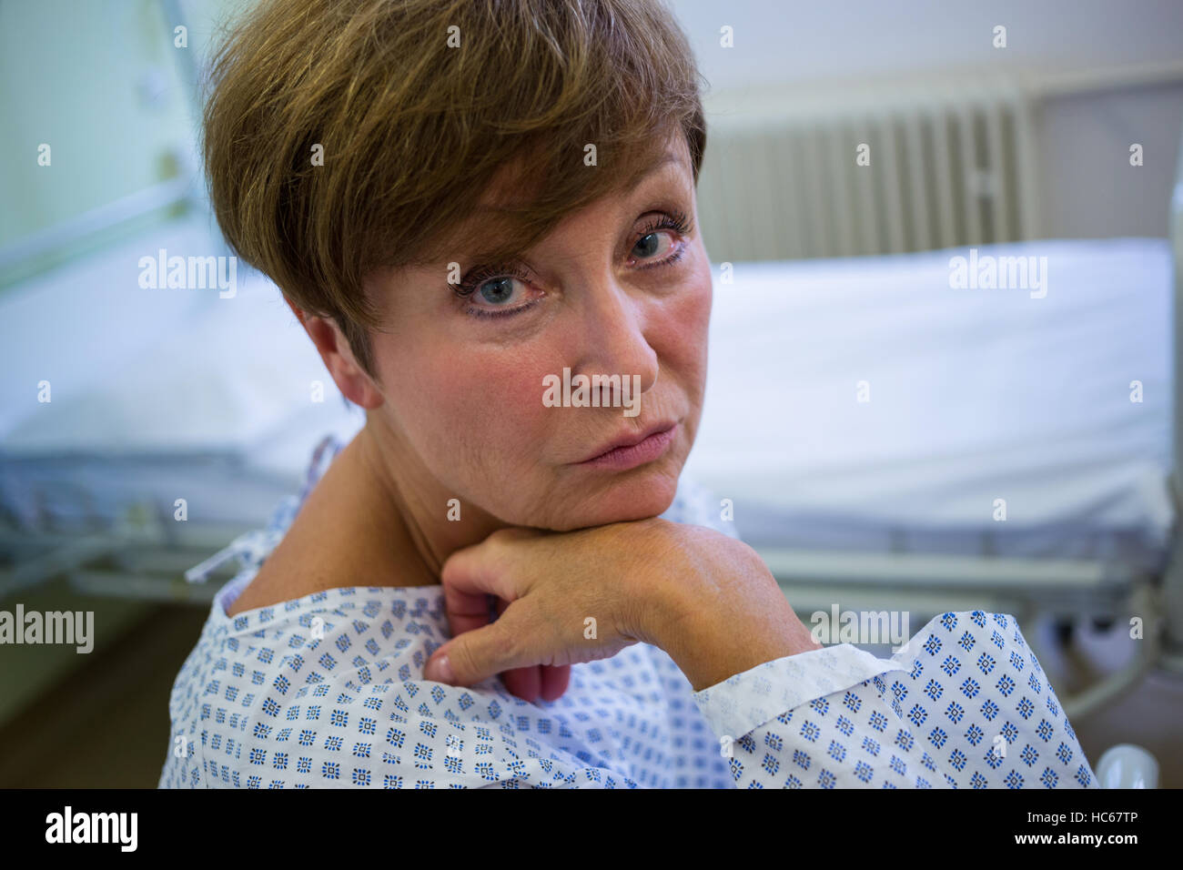 Portrait of sad senior patient sitting on a bed Stock Photo - Alamy