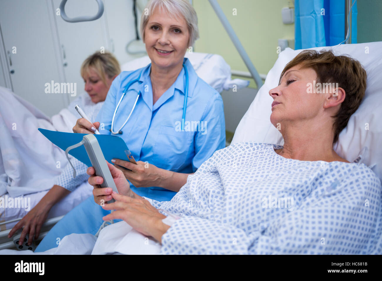 Patient using medical device and nurse sitting next to the bed Stock ...