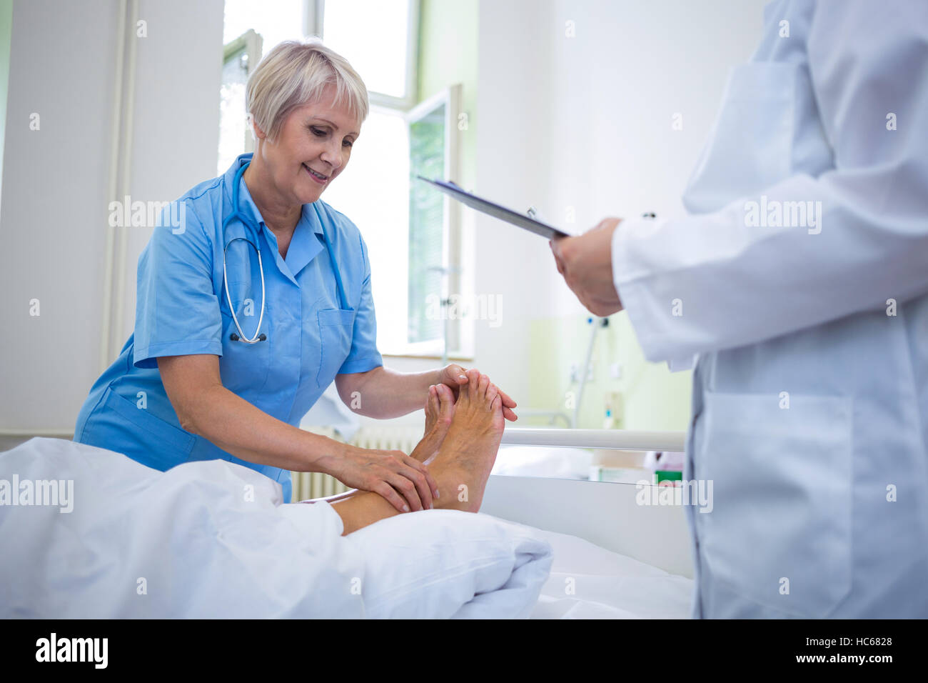 Nurse giving foot treatment to patient Stock Photo - Alamy