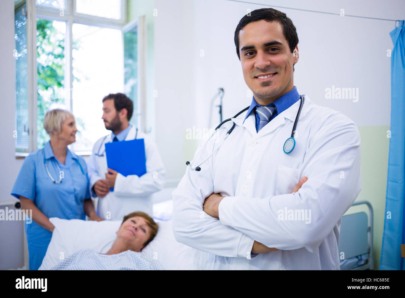 Smiling doctor standing with arms crossed in hospital Stock Photo - Alamy
