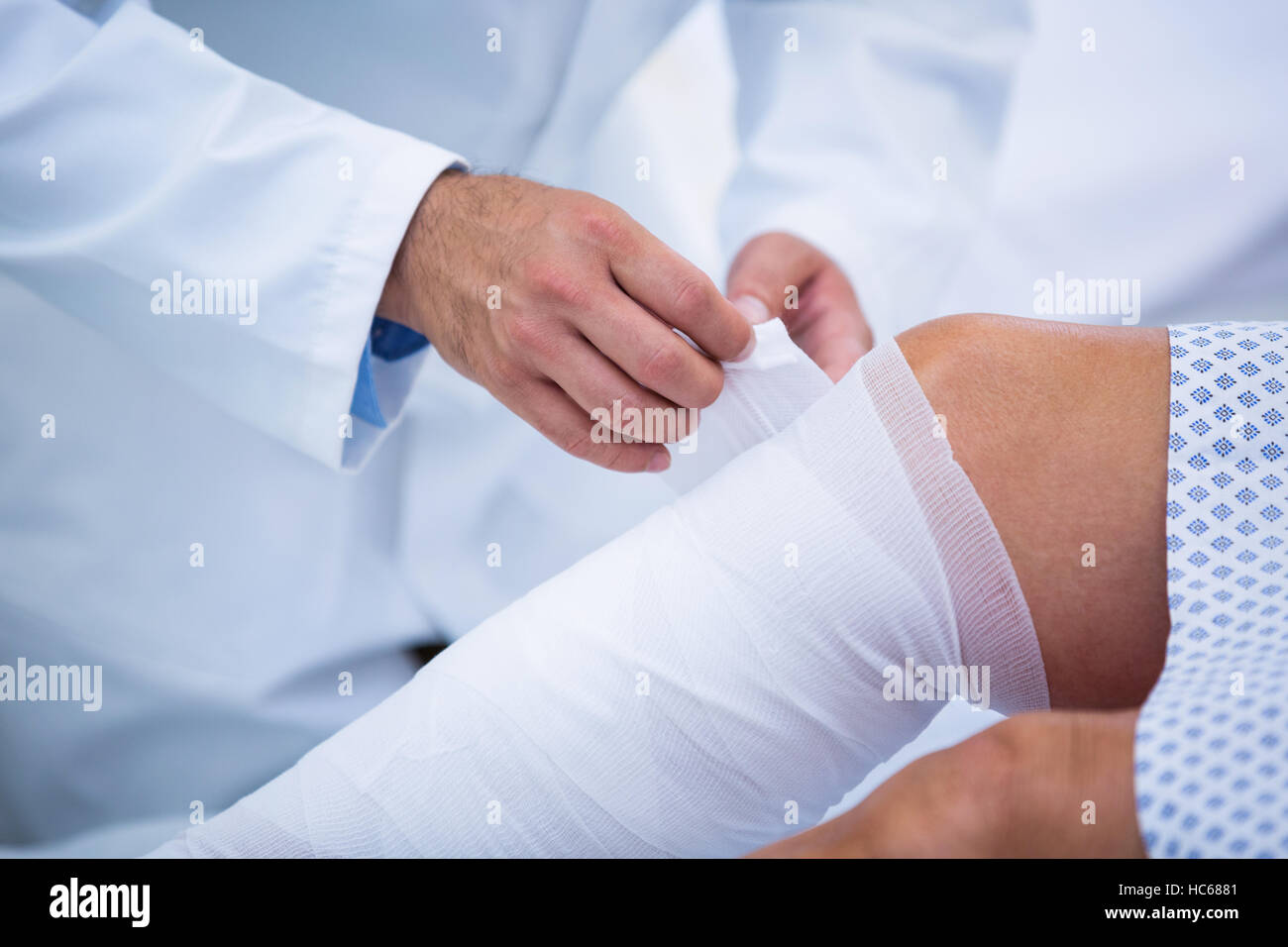 Doctor bandaging leg of patient Stock Photo - Alamy