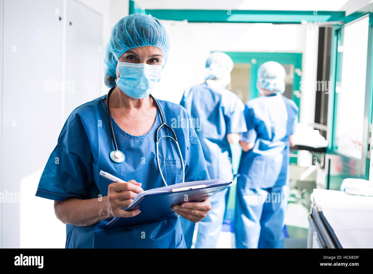 Female surgeon writing on clipboard in corridor Stock Photo - Alamy